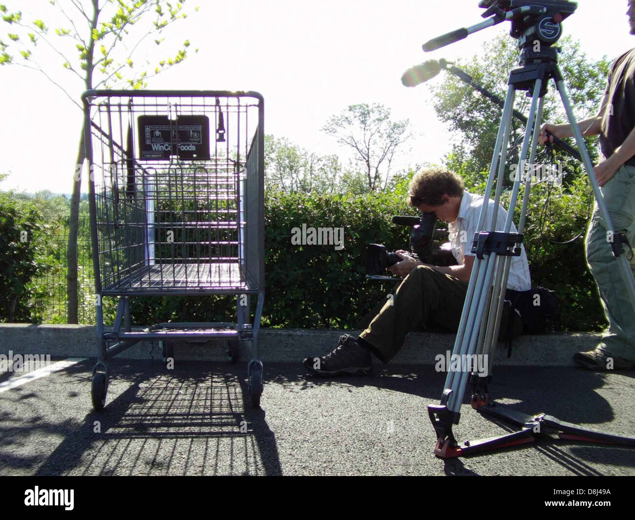 A film crew working in an urban area near a grocery store parking lot ...
