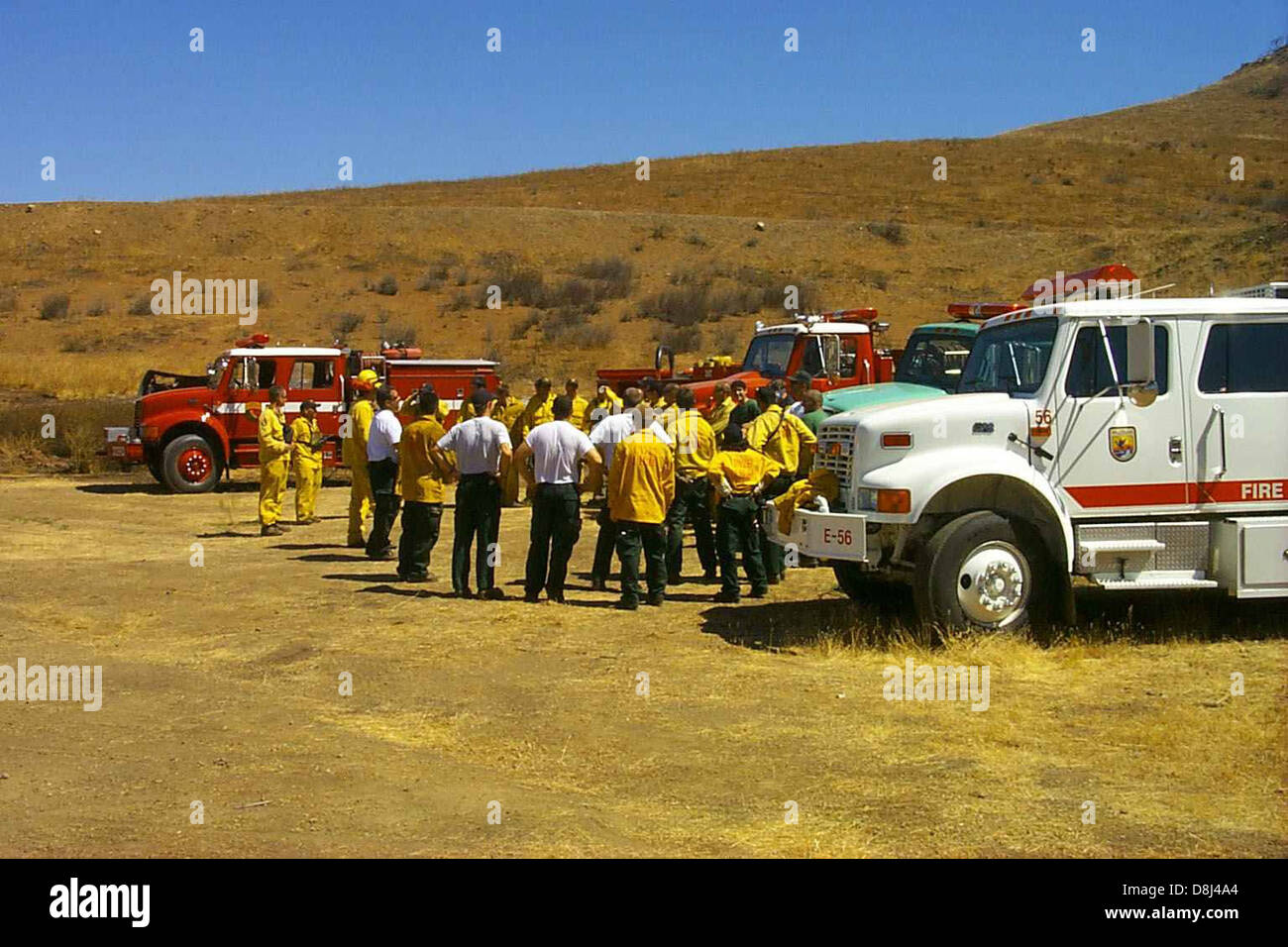 Firefighters standing next to their fire truck, fully equipped with ...