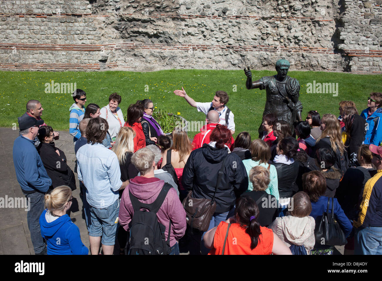 Tourists listen to a tour guide speaking at the Julius Caesar statue at ...