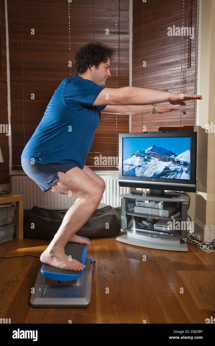 Man practicing his snowboarding technique on a simulator in his home ...