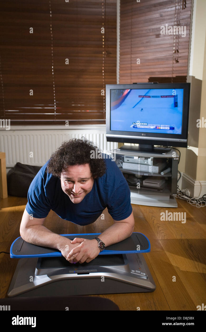 Man practicing his snowboarding technique on a simulator in his home ...