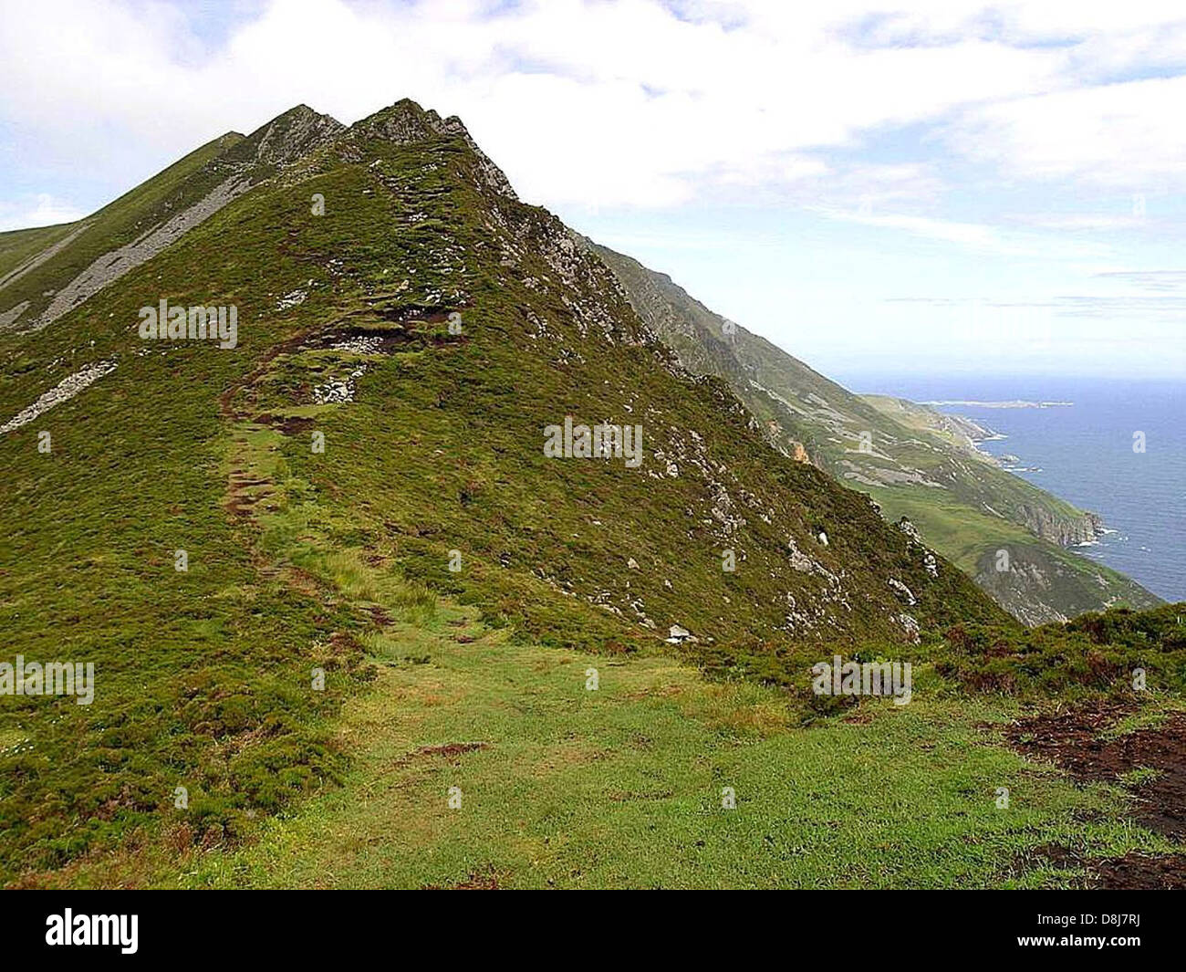 The image captures green cliffs in Ireland, with steep, rugged terrain ...