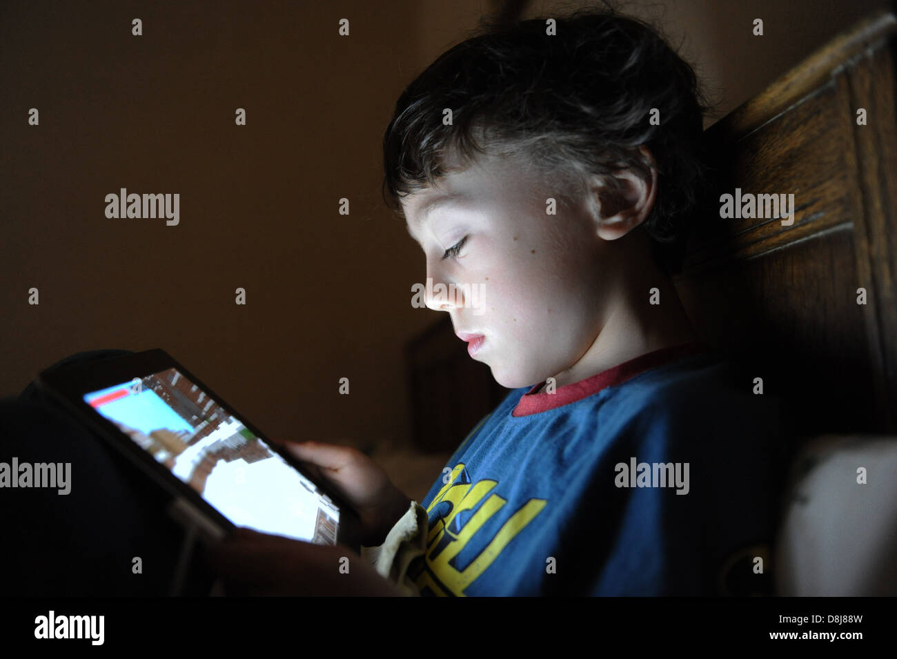 An 8 year old boy playing a computer game on his Apple IPAD in his ...