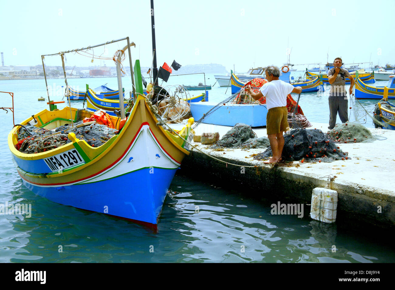 Two fishermen checking nets at Marsaxlokk, Malta Stock Photo - Alamy