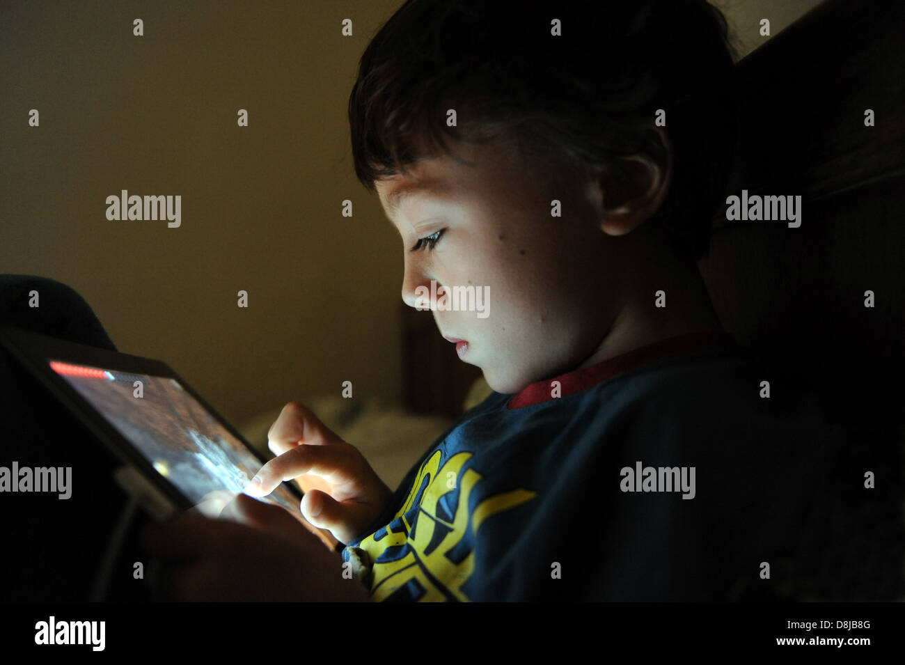 An 8 year old boy playing a computer game on his Apple IPAD in his ...