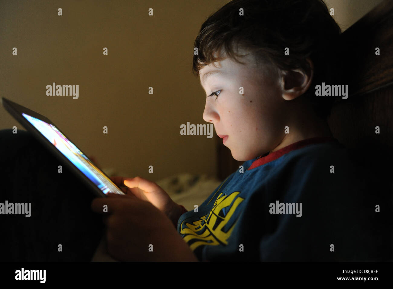 An 8 year old boy playing a computer game on his Apple IPAD in his ...