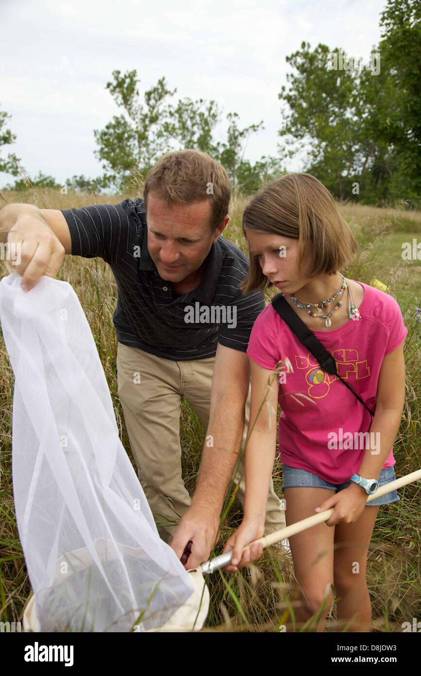 A man and a girl use an insect mesh to catch insects, engaging in a fun ...