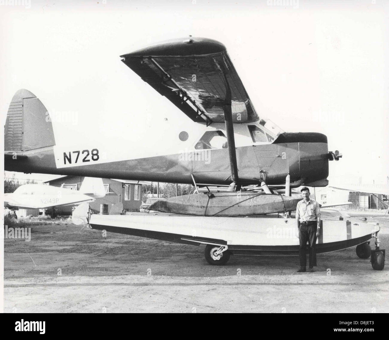 A man stands in front of a float plane, which is typically used for ...
