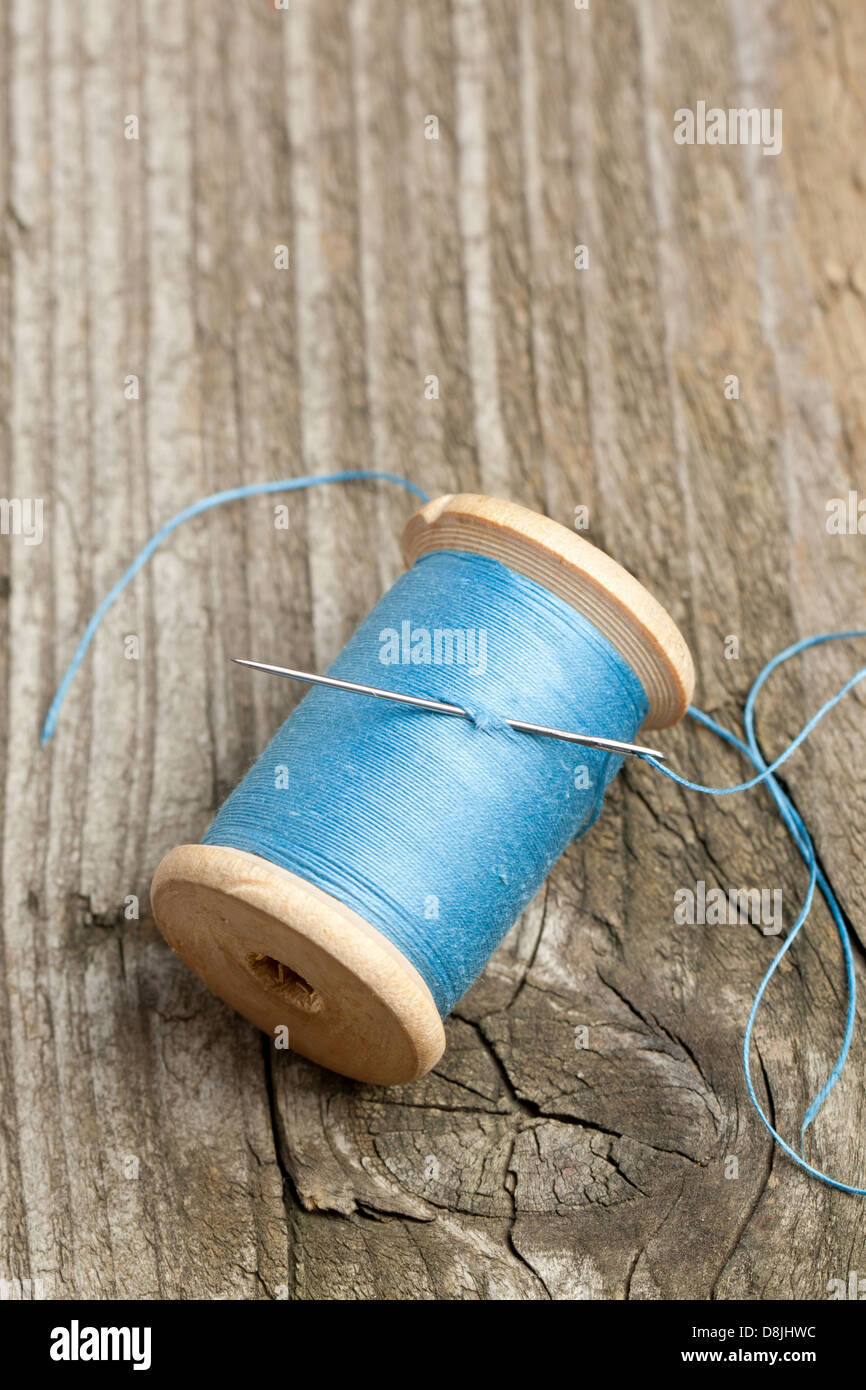 Top view on spool of blue thread and needle on old wooden table Stock ...