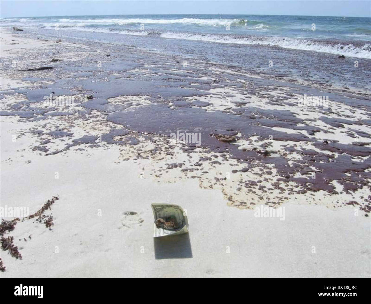 An oil slick washing up on the shore, presenting a negative ...