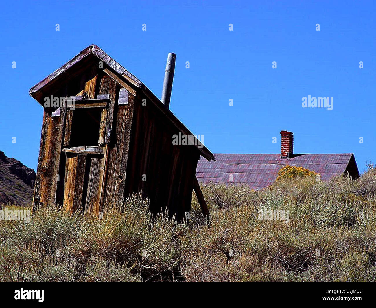 The image shows rustic outhouses in Bodie, a well-preserved ghost town ...