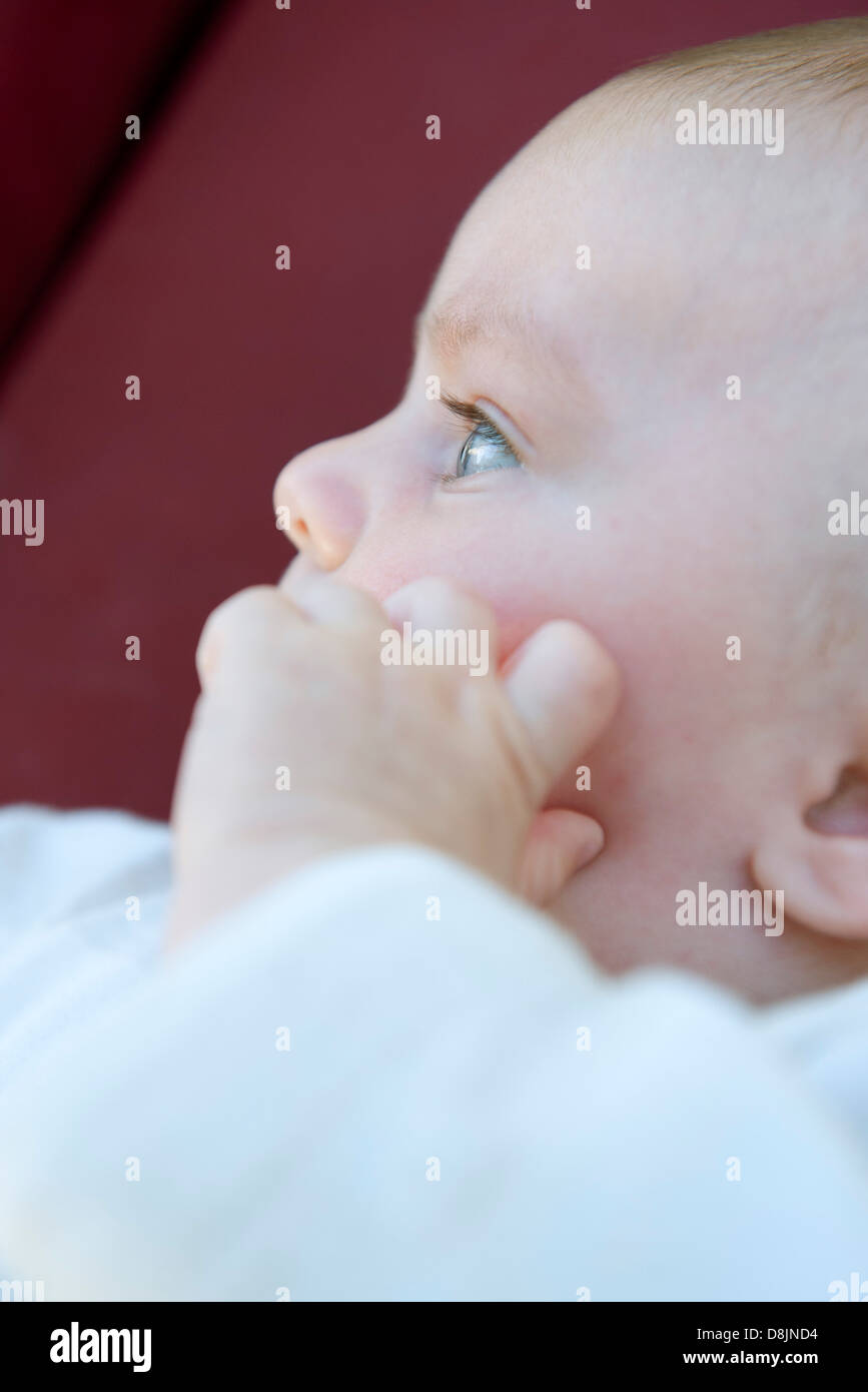Baby with hand on face, side view Stock Photo - Alamy