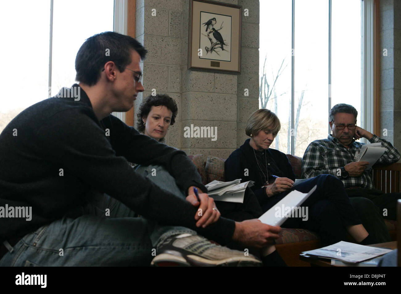 A group of people gathered together, reading notes and engaging in ...