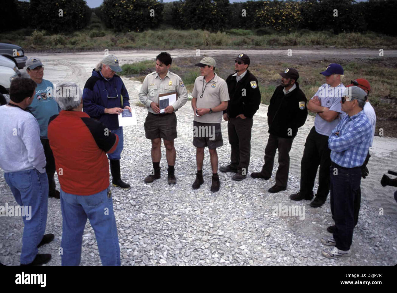 A group of people are engaged in conversation, standing together in a ...