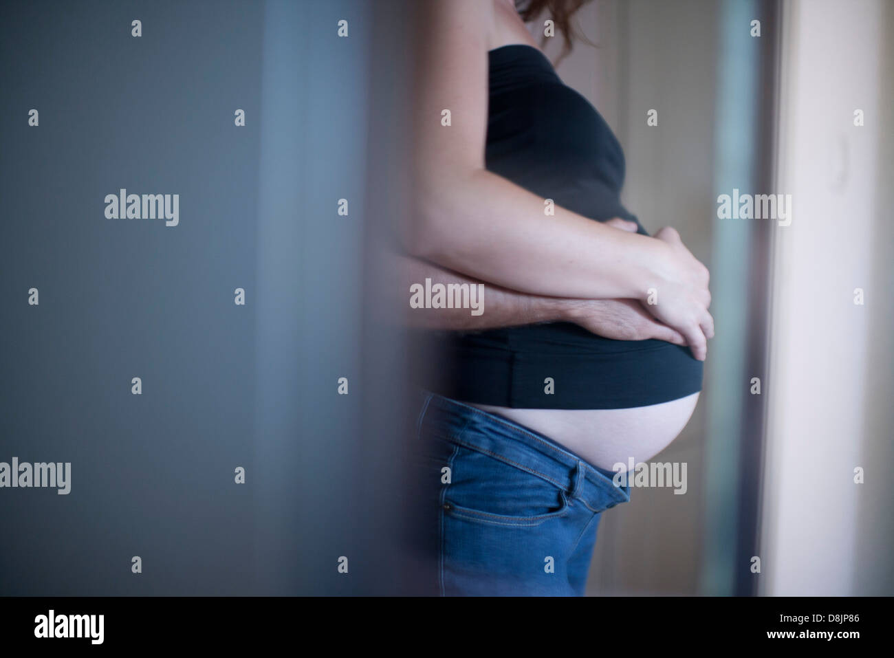 Husband wrapping arms around pregnant wife, side view Stock Photo - Alamy