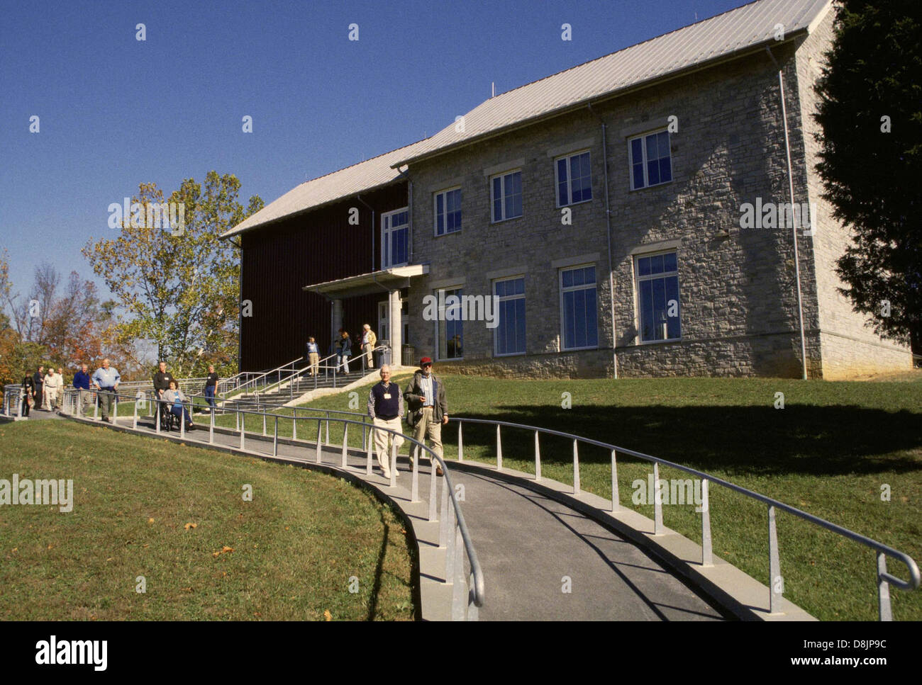 This image shows a diverse group of people walking along a sidewalk ...