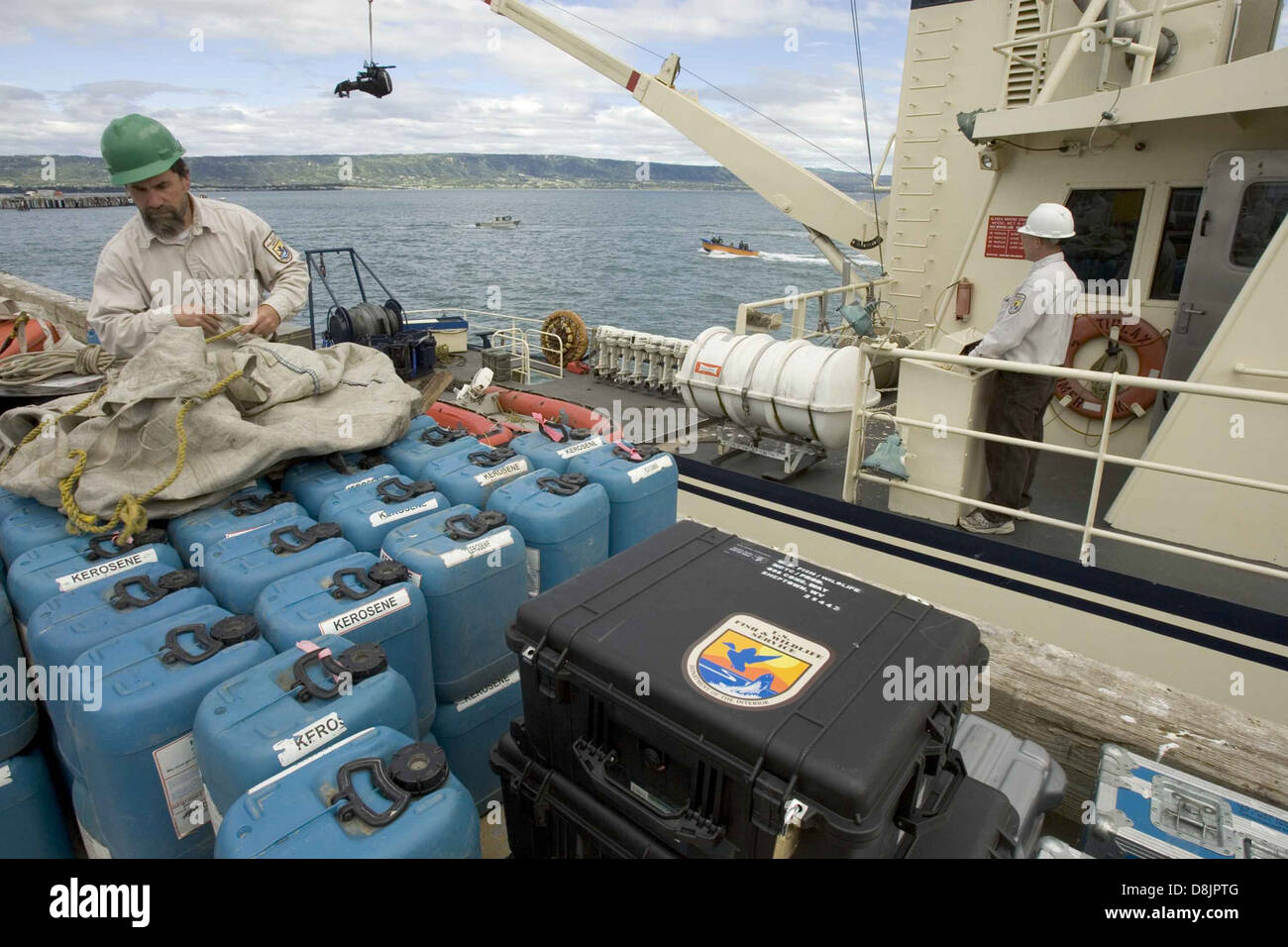 A group of people are seen working on a large motorized ship. The photo ...