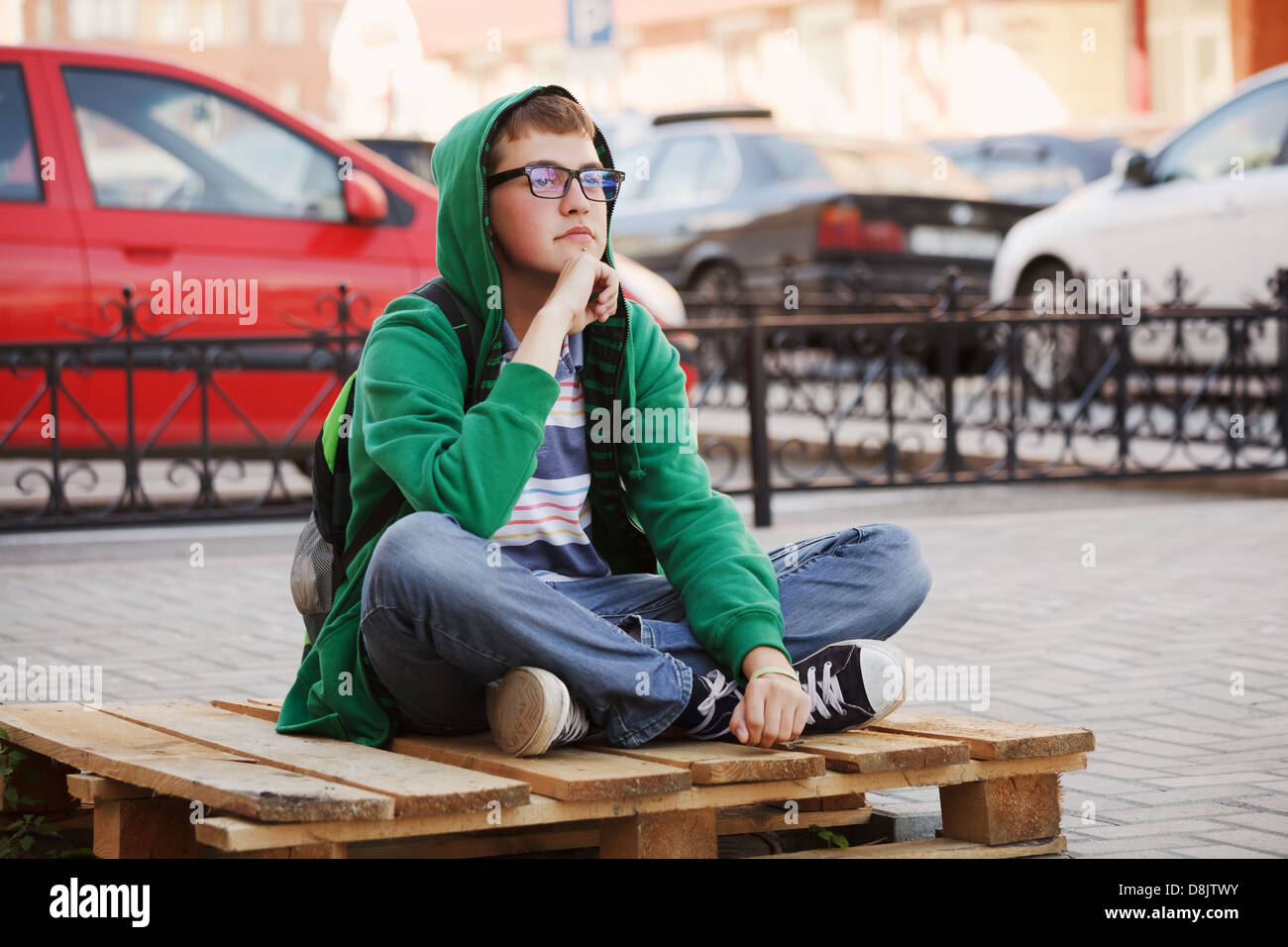 Young man sitting against a city traffic Stock Photo - Alamy
