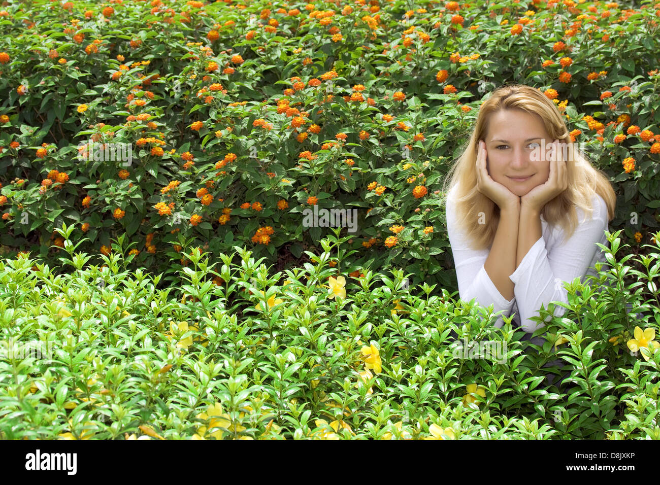 Young woman sitting in flowers Stock Photo - Alamy