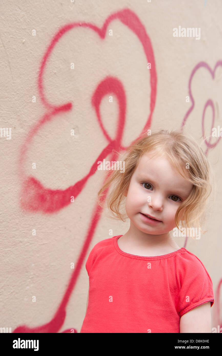 Little girl by wall with flower graffiti, portrait Stock Photo - Alamy