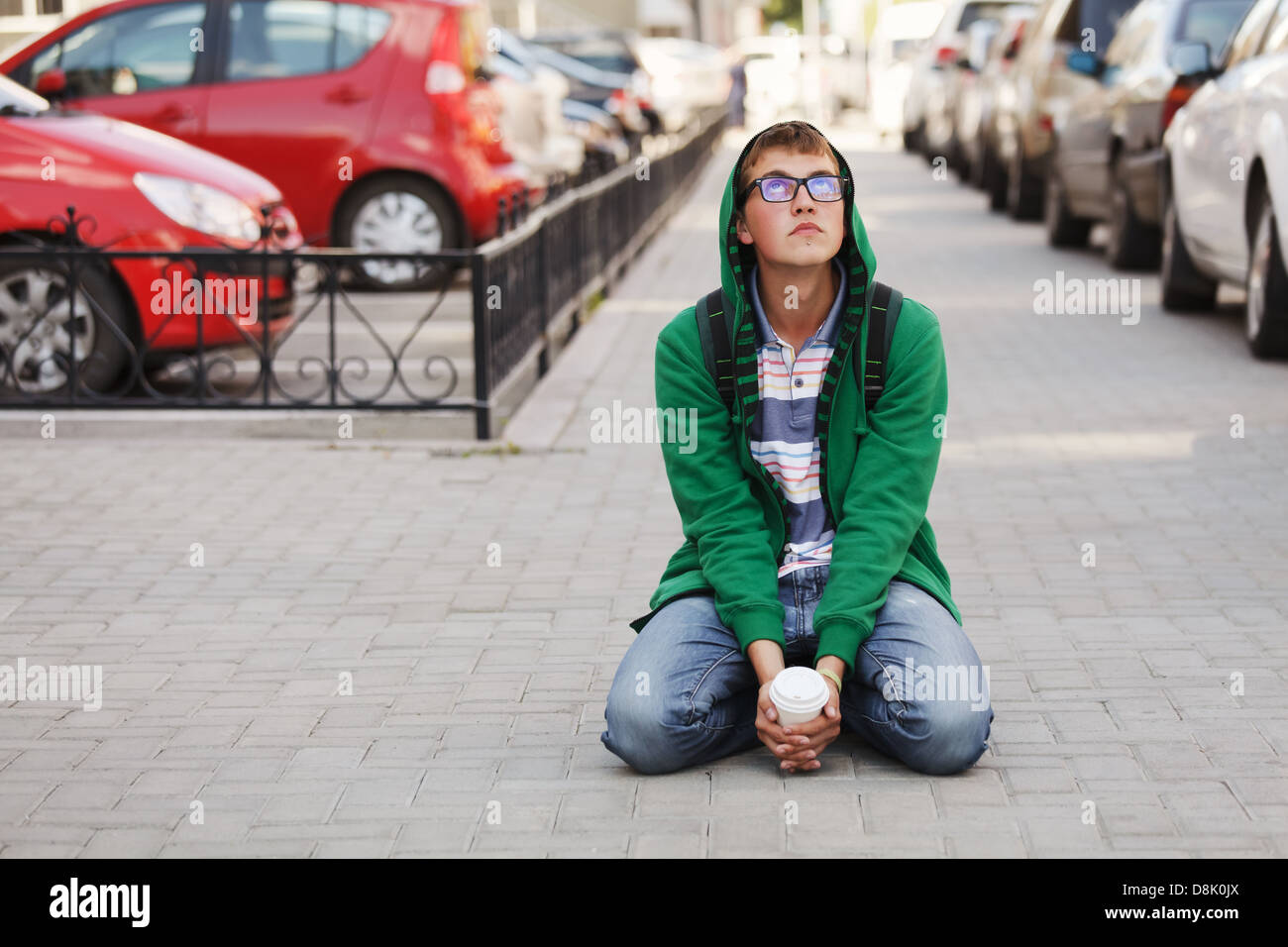Young man sitting against a city traffic Stock Photo - Alamy