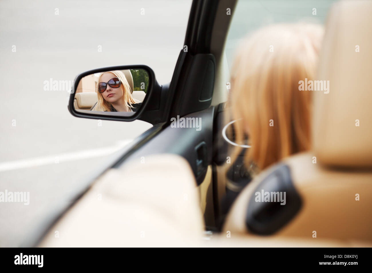 Young woman looking in the car mirror Stock Photo - Alamy