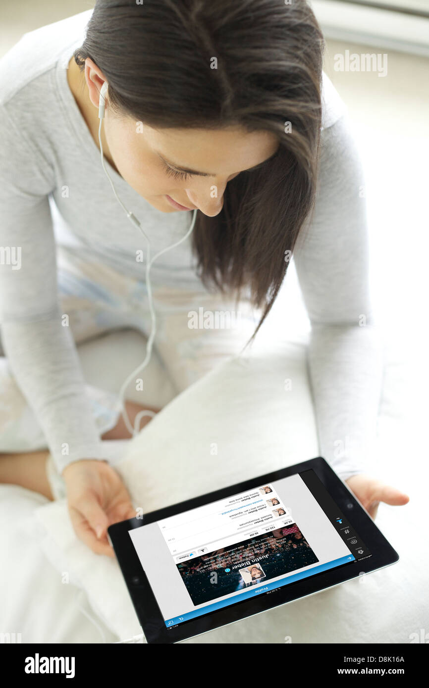 Young woman using headphones reading Twitter newsfeed on her ipad Stock ...