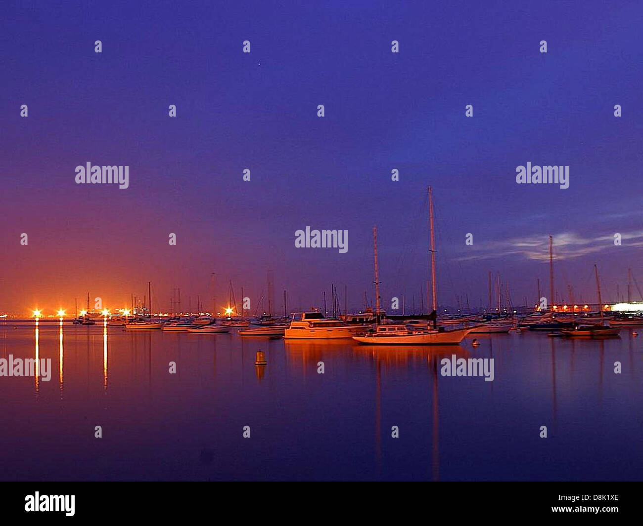 Sailboats gently float in a calm bay, their sails catching the wind ...