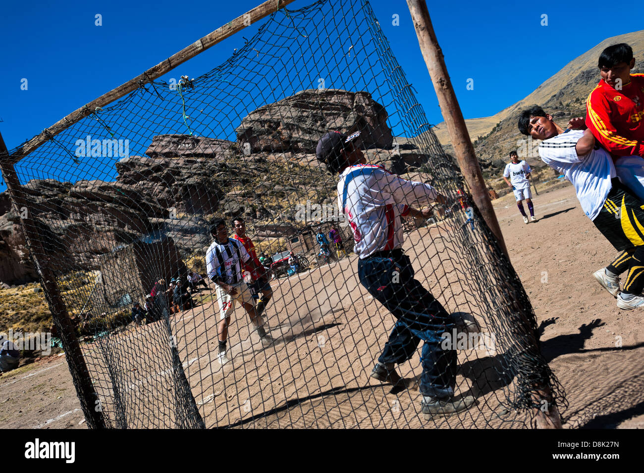 Indigenous men play football on a dusty football pitch in the rural ...