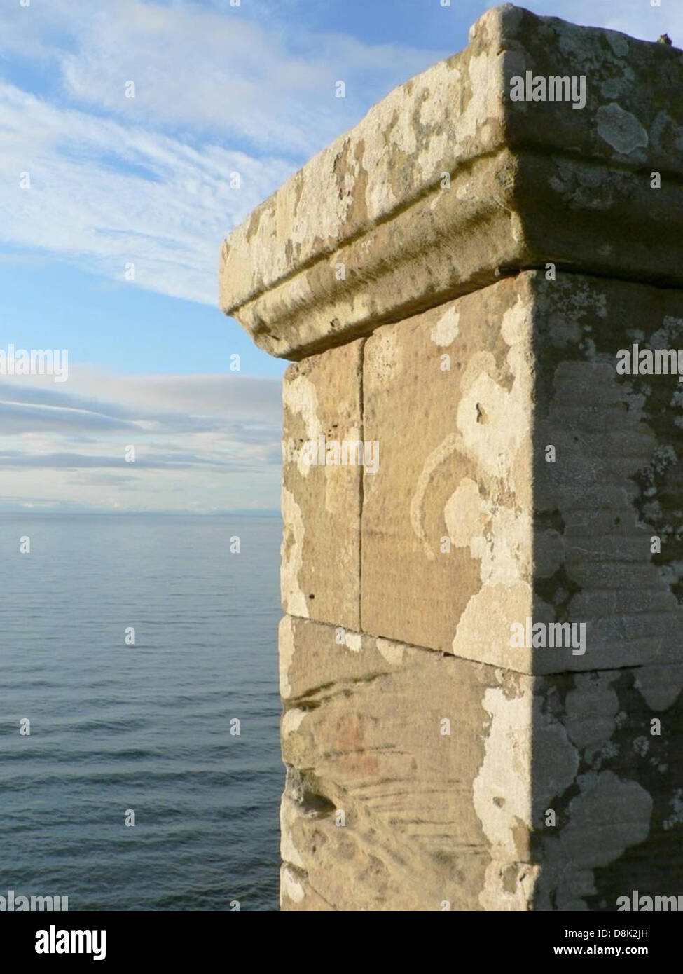 A seaside castle wall overlooks the ocean, showing its weathered stone ...