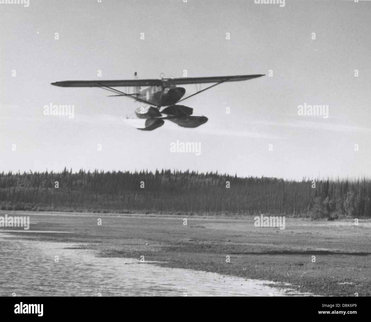 A small float plane flies over a vast natural landscape, showcasing its ...