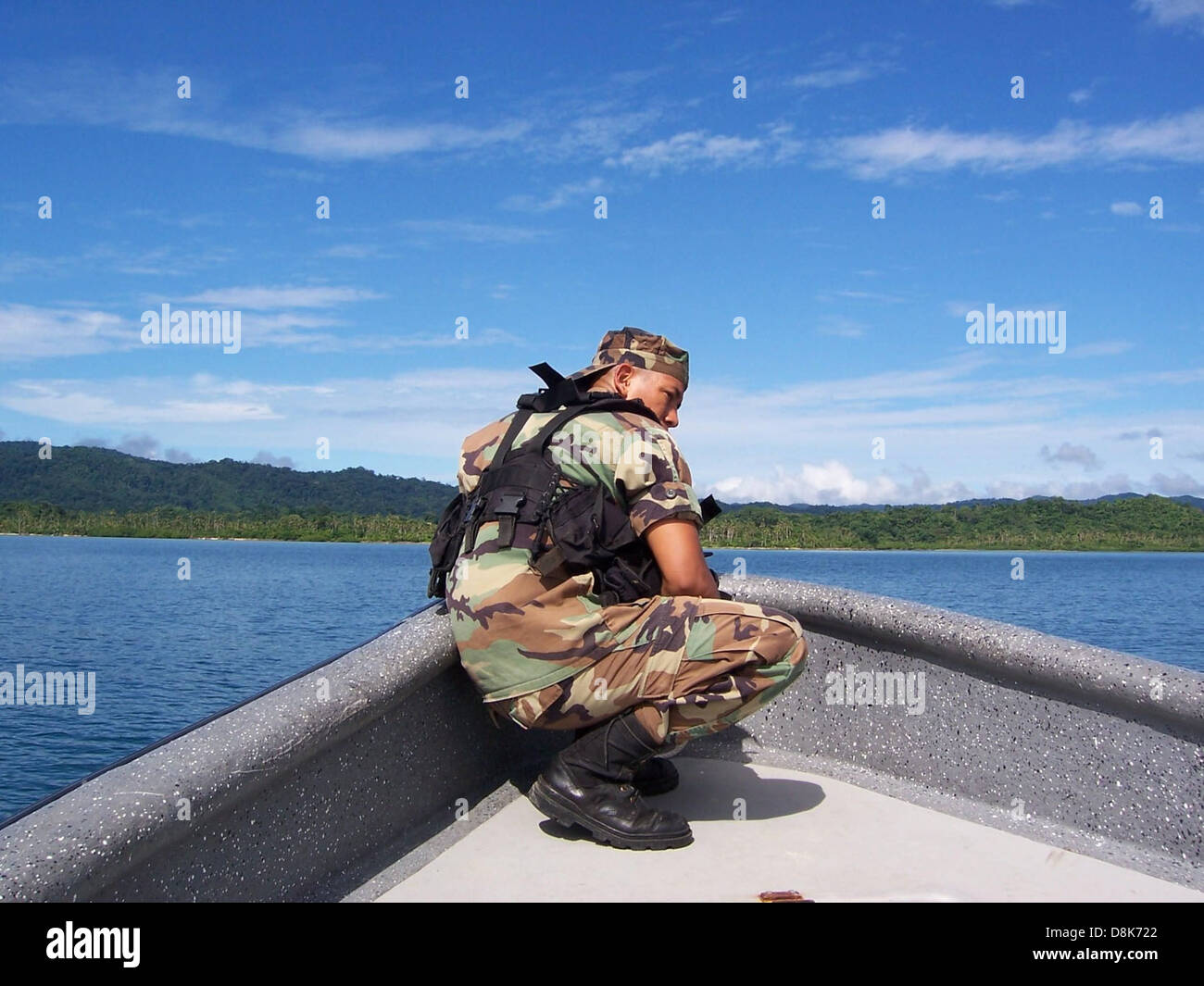 A soldier aboard a military boat, poised and focused during a naval ...