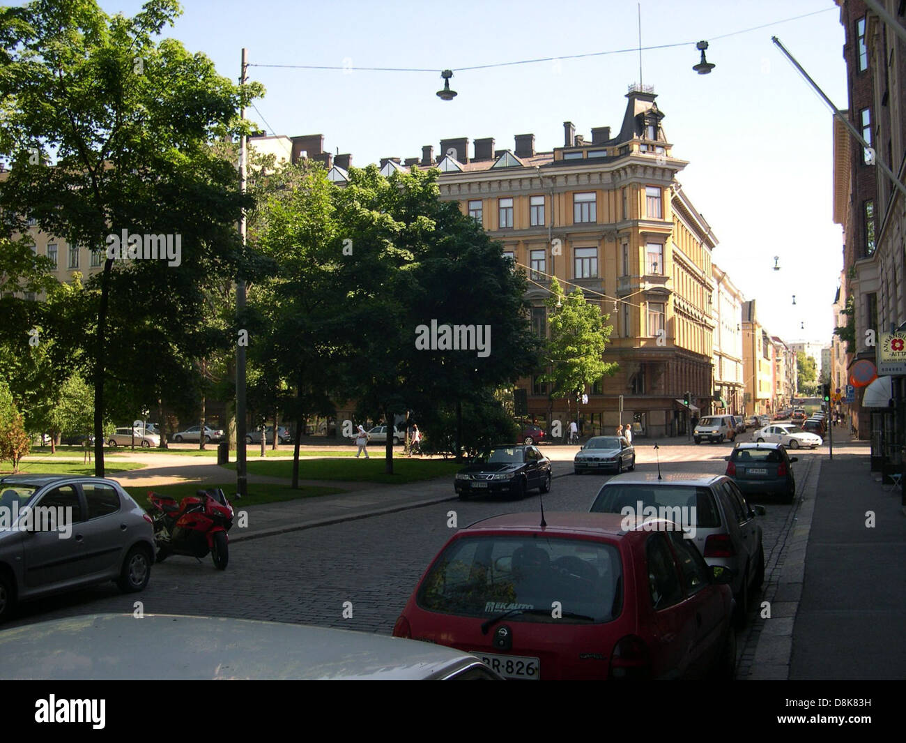 A well-maintained street park featuring green spaces, benches, trees ...