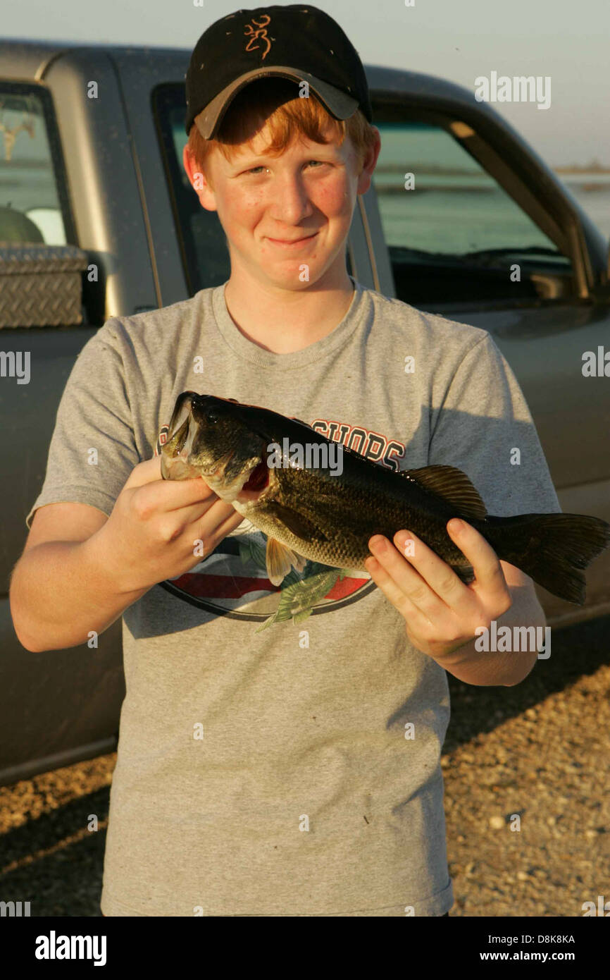 An image of a teenage boy with red hair holding a freshly caught bass ...