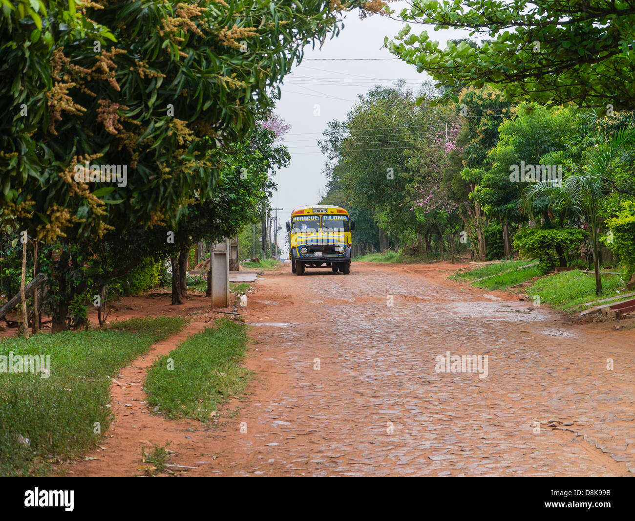 A public bus runs along a rural route with a semi-paved road outside of ...