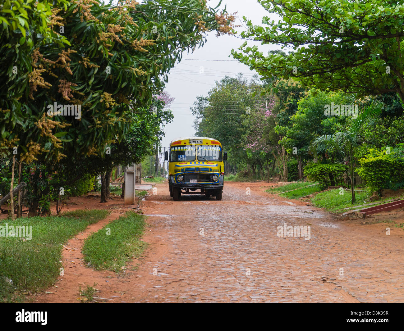 A public bus runs along a rural route with a semi-paved road outside of ...