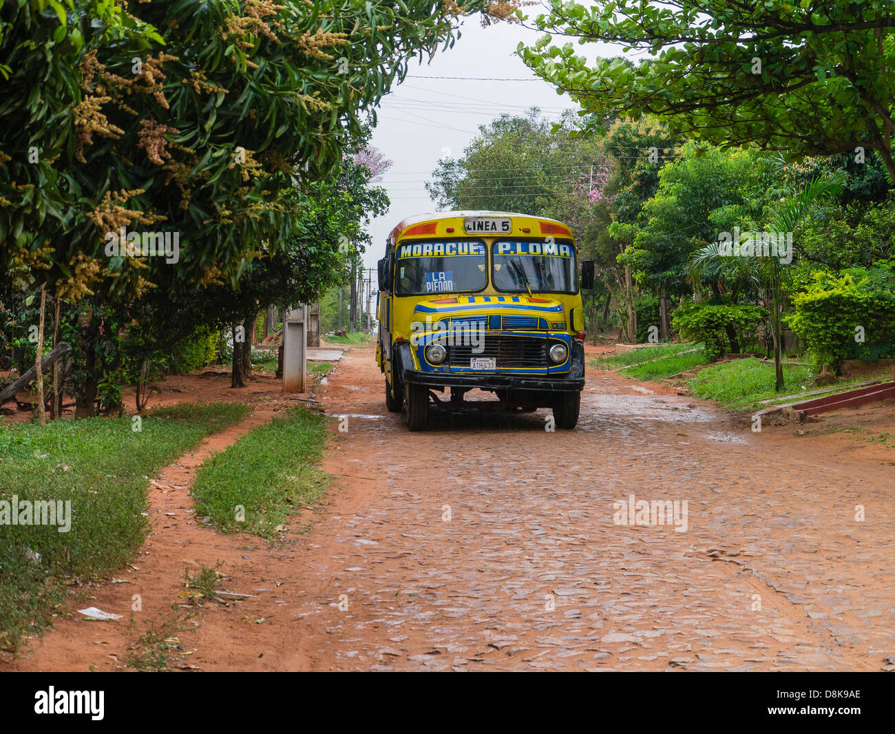 A public bus runs along a rural route with a semi-paved road outside of ...