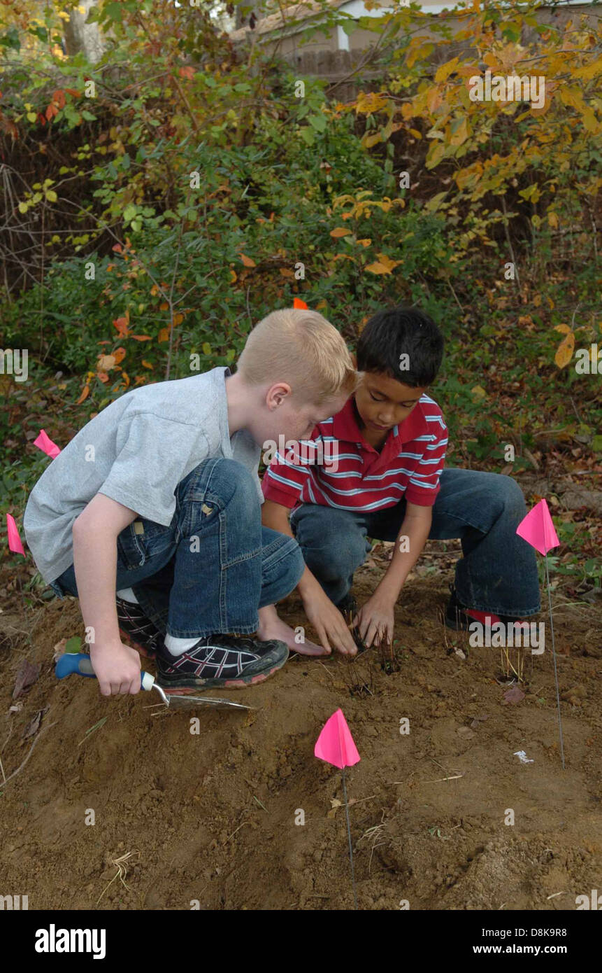 Two boys are seen playing outside, digging the ground as part of an ...