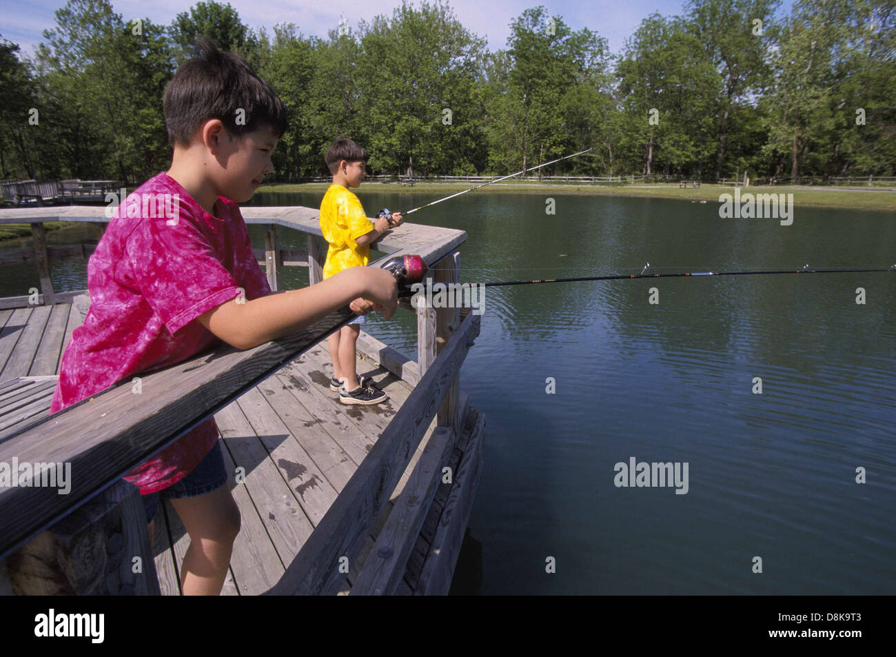 Two children, each with their own fishing rods, enjoy a peaceful day of ...