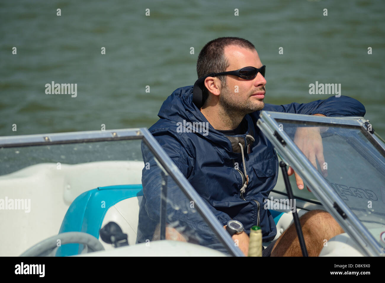 Man sitting in a motorboat looking away Stock Photo - Alamy