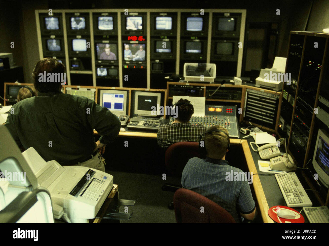 In a video production studio, workers observe a bank of monitors ...
