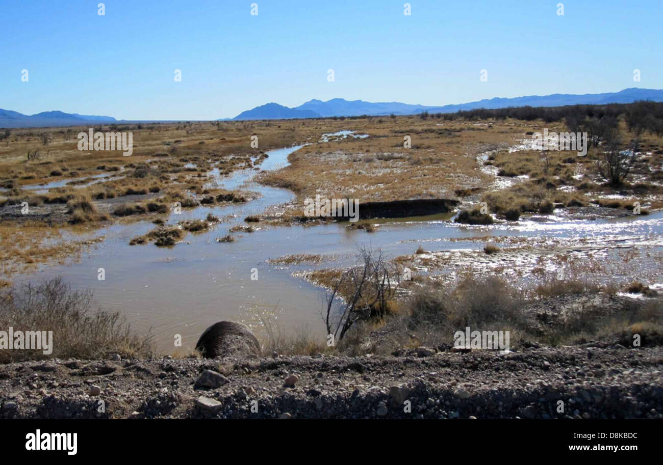Water flows out of a runoff pipe, causing flooding in a low-lying area ...