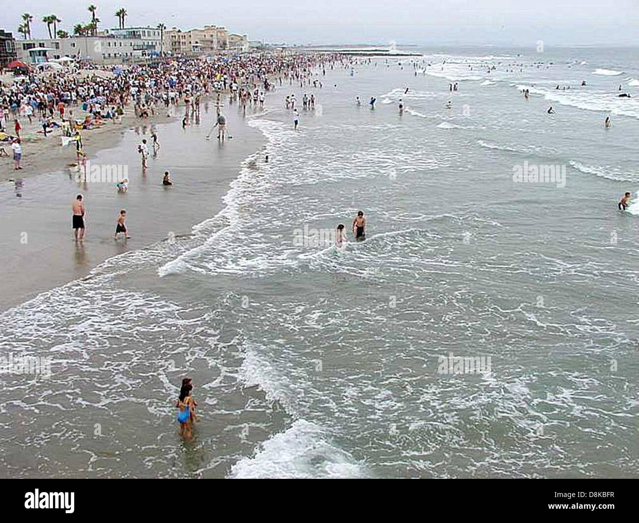 This image captures the busy scene of waves crashing on a beach, with ...