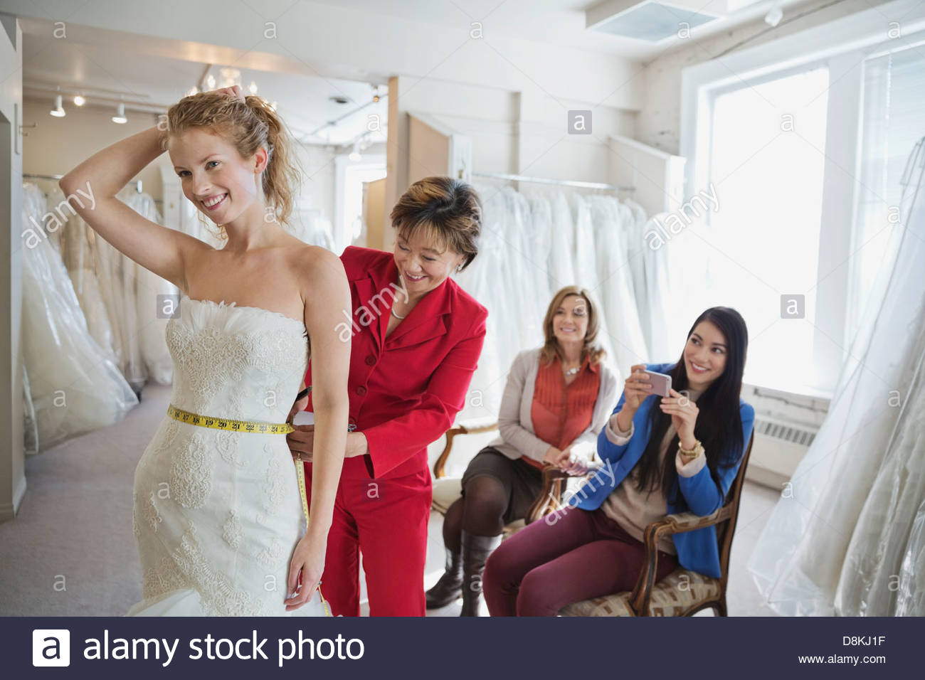 Woman tailor measuring woman in wedding dress at bridal store Stock ...