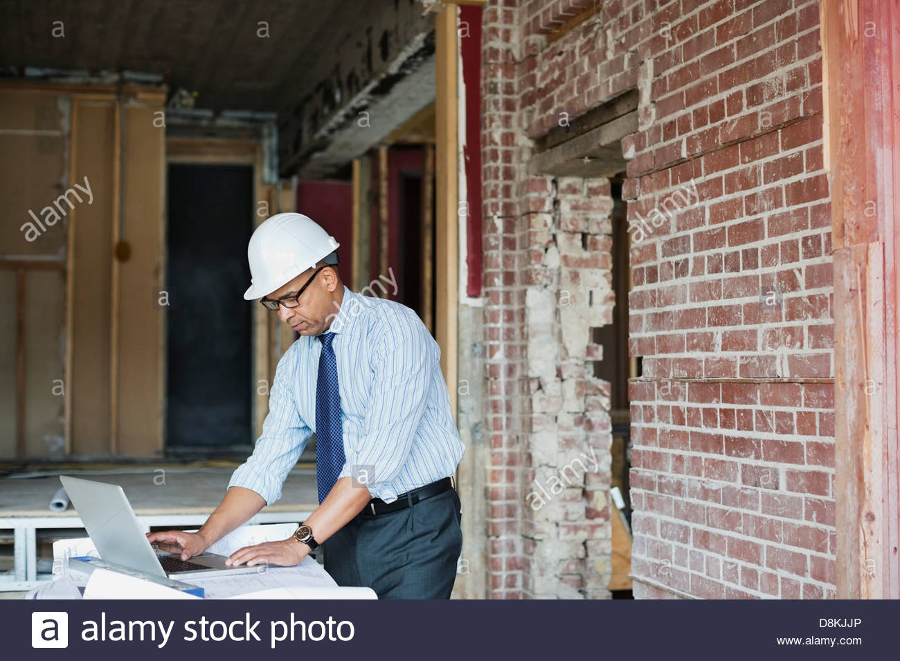 African American male contractor using tablet PC with stacked wooden ...