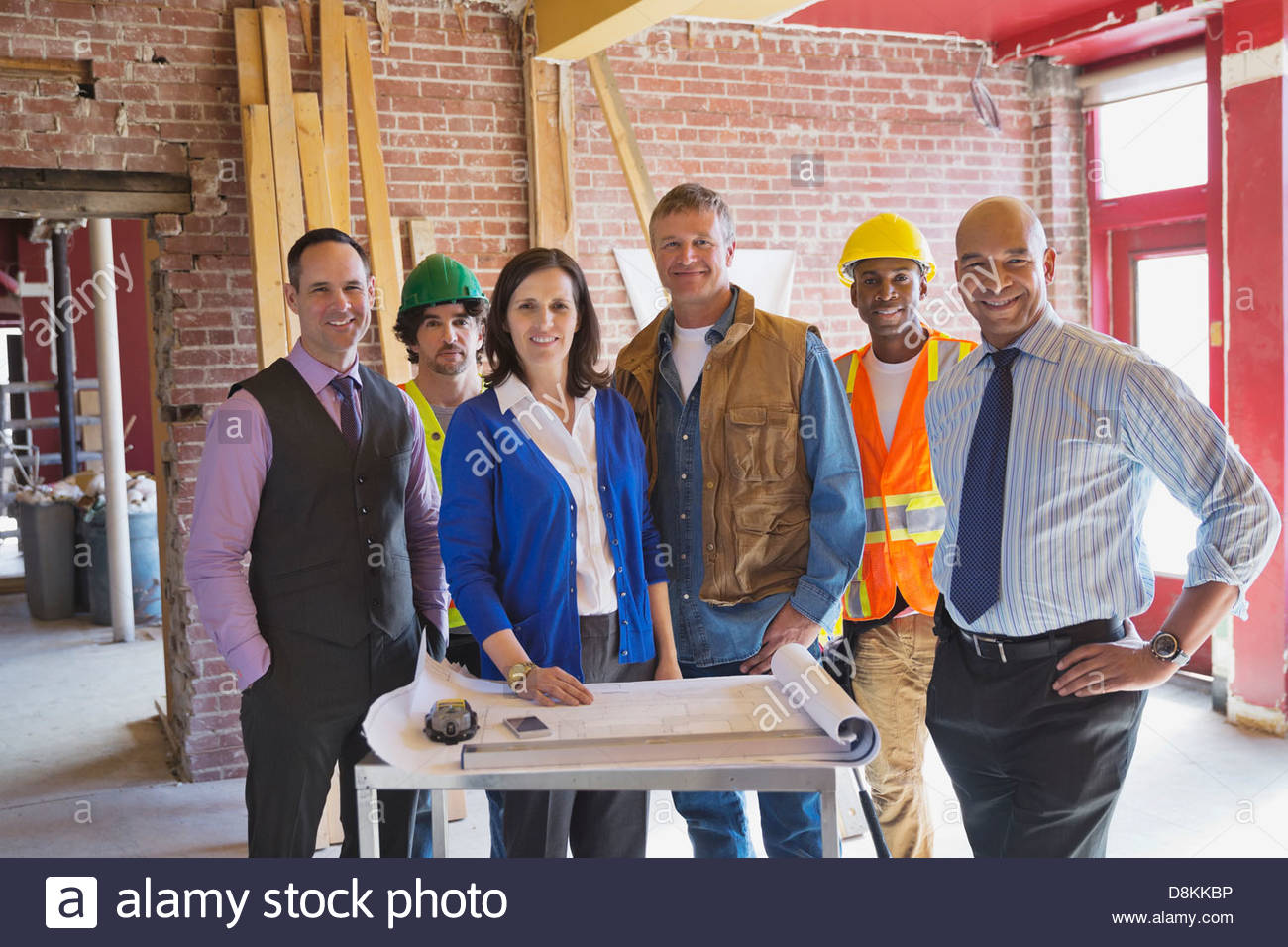 Portrait of team of architects and tradesmen standing at construction ...