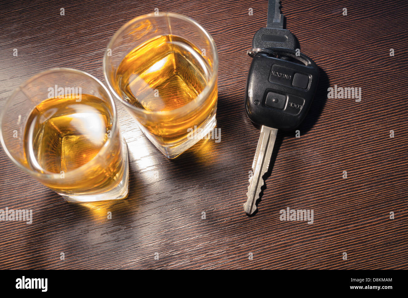two whiskey shots on the bar counter with car key between them; focus ...