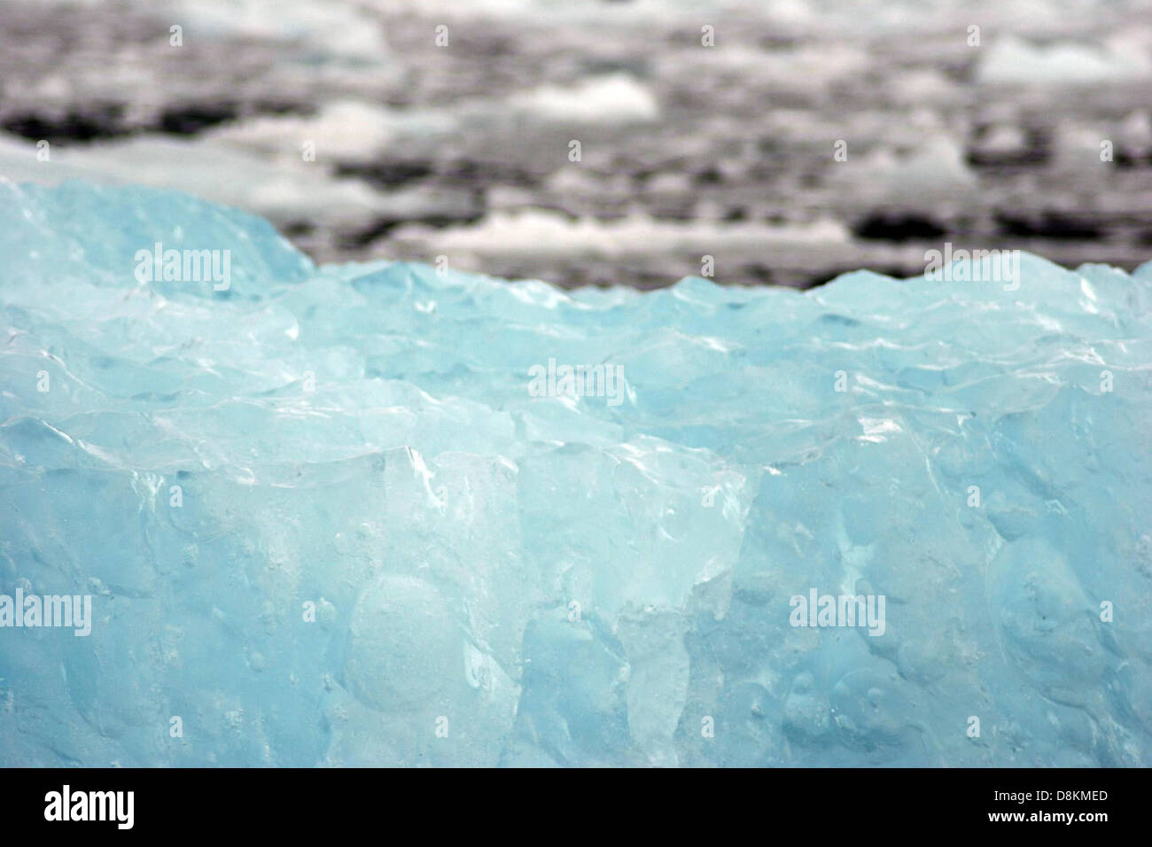 A large blue iceberg floats in the ocean, its icy surface contrasting ...