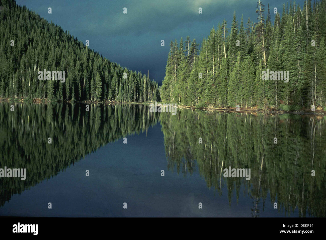 The calm surface of the lake reflects the surrounding scenery, creating ...