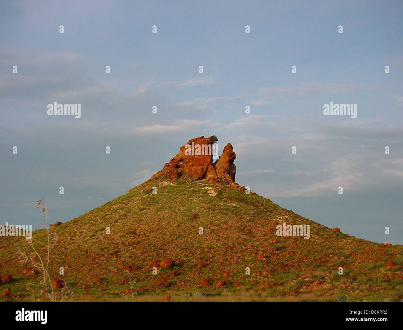 A simple view of a small hill with gentle slopes, surrounded by grass ...